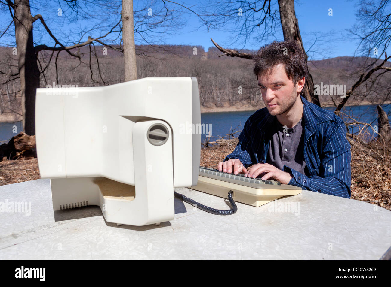 A Young Man typing on his Computer in the Outdoors and surrounded by ...
