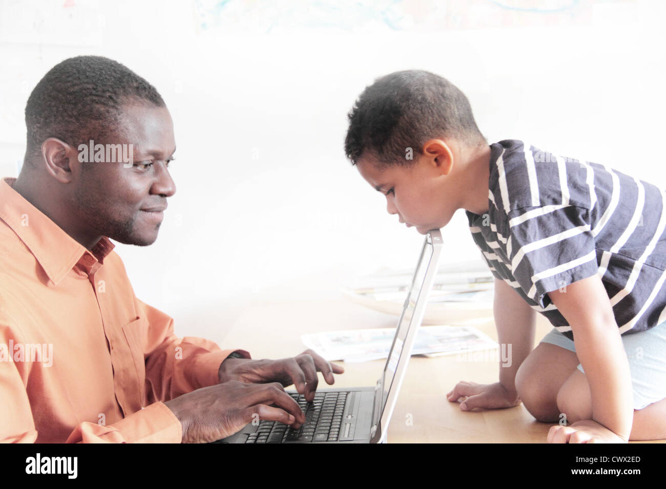 Boy watching father use laptop Stock Photo - Alamy