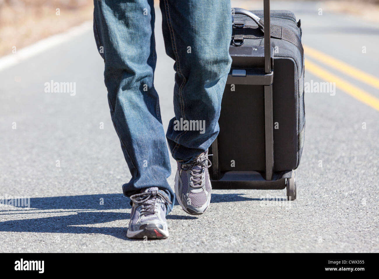 Young Man walking and traveling on a Road with his rolling suitcase ...
