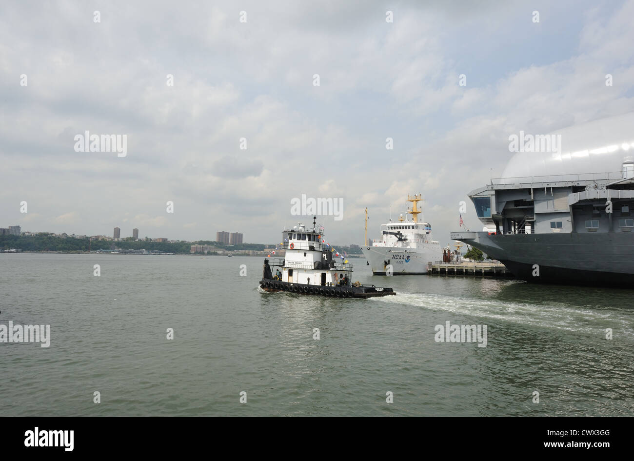 A push tugboat pulls into the Hudson River with a National Oceanic and ...