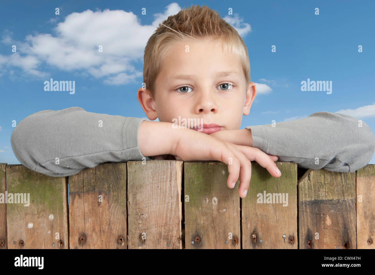 little boy looking from above a fence. Clouds in the background Stock ...