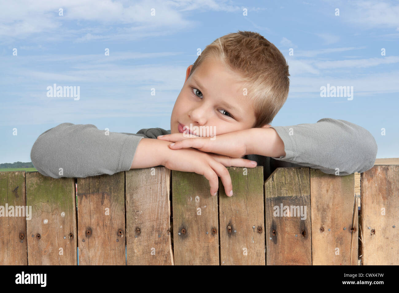 little boy looking from above a fence. Clouds in the background Stock ...