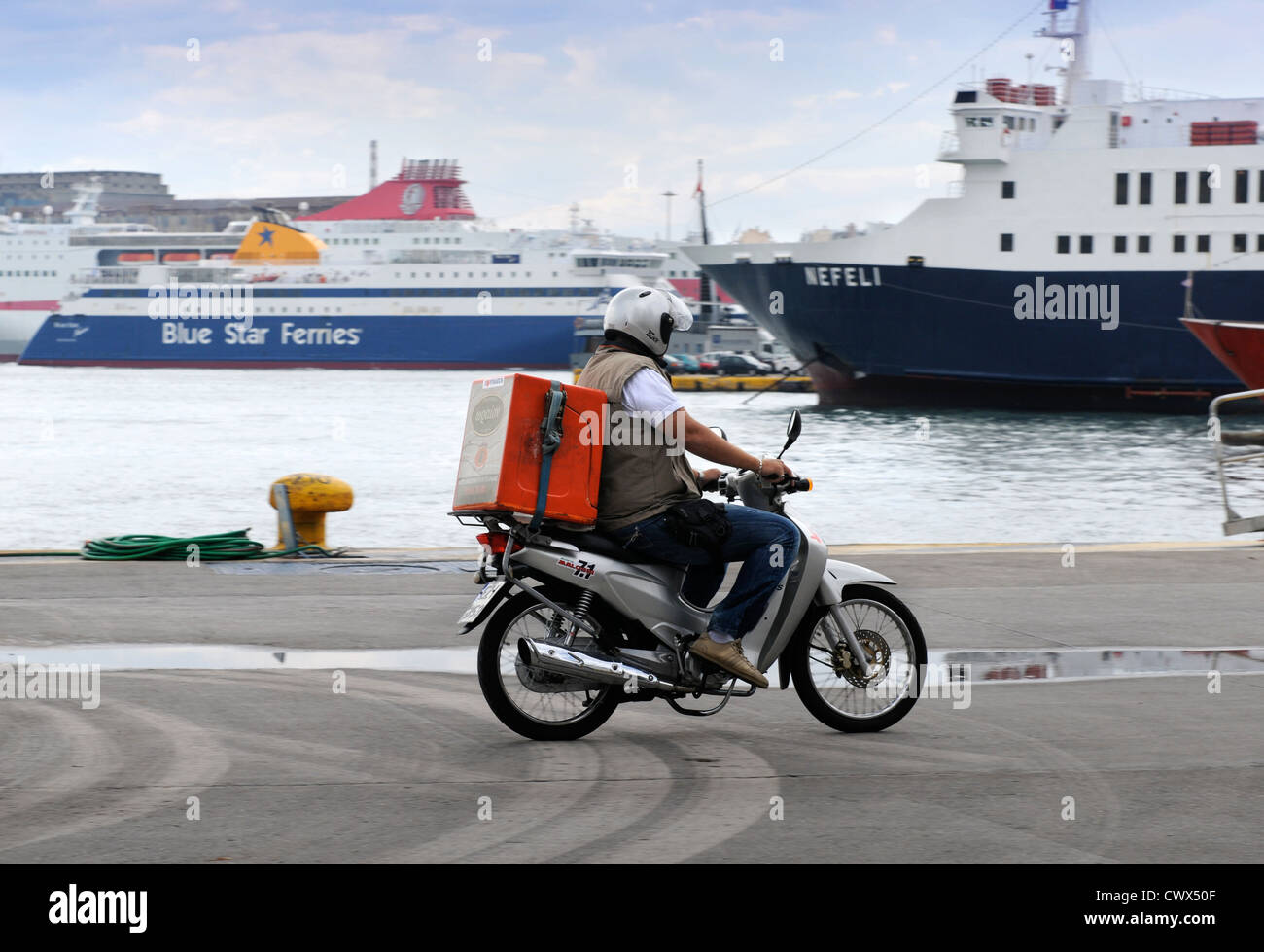 A motorbike delivery man on the dock at the port of Piraeus in Athens ...