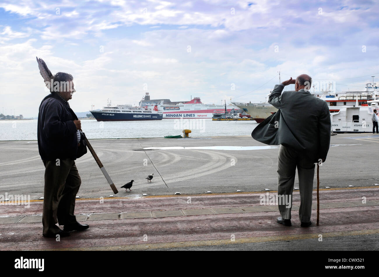 Two Greek men watch passenger ferries at the port of Piraeus in Athens ...