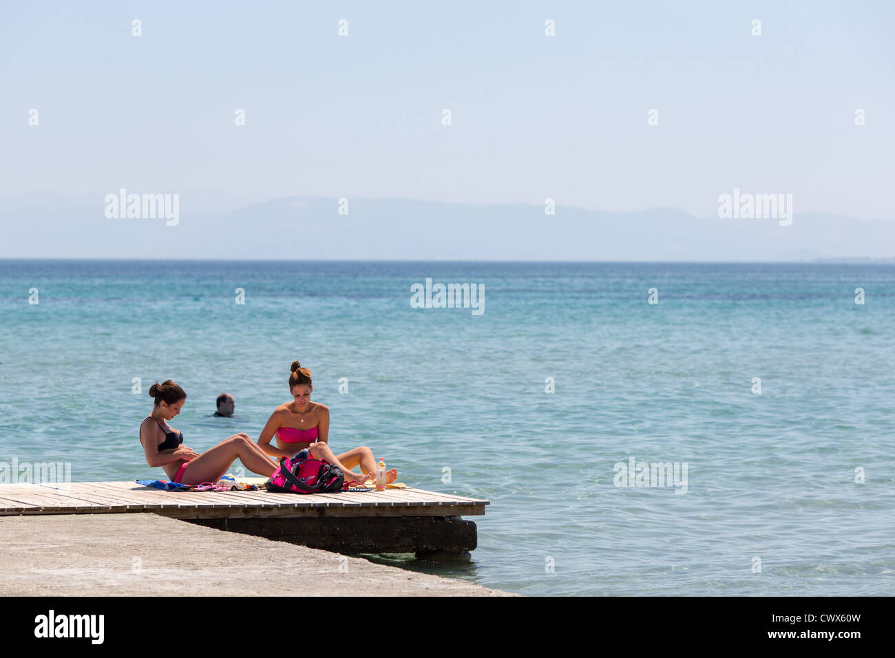 Female tourists sun bathing on the beach of Moraitika, Corfu, Ionian ...