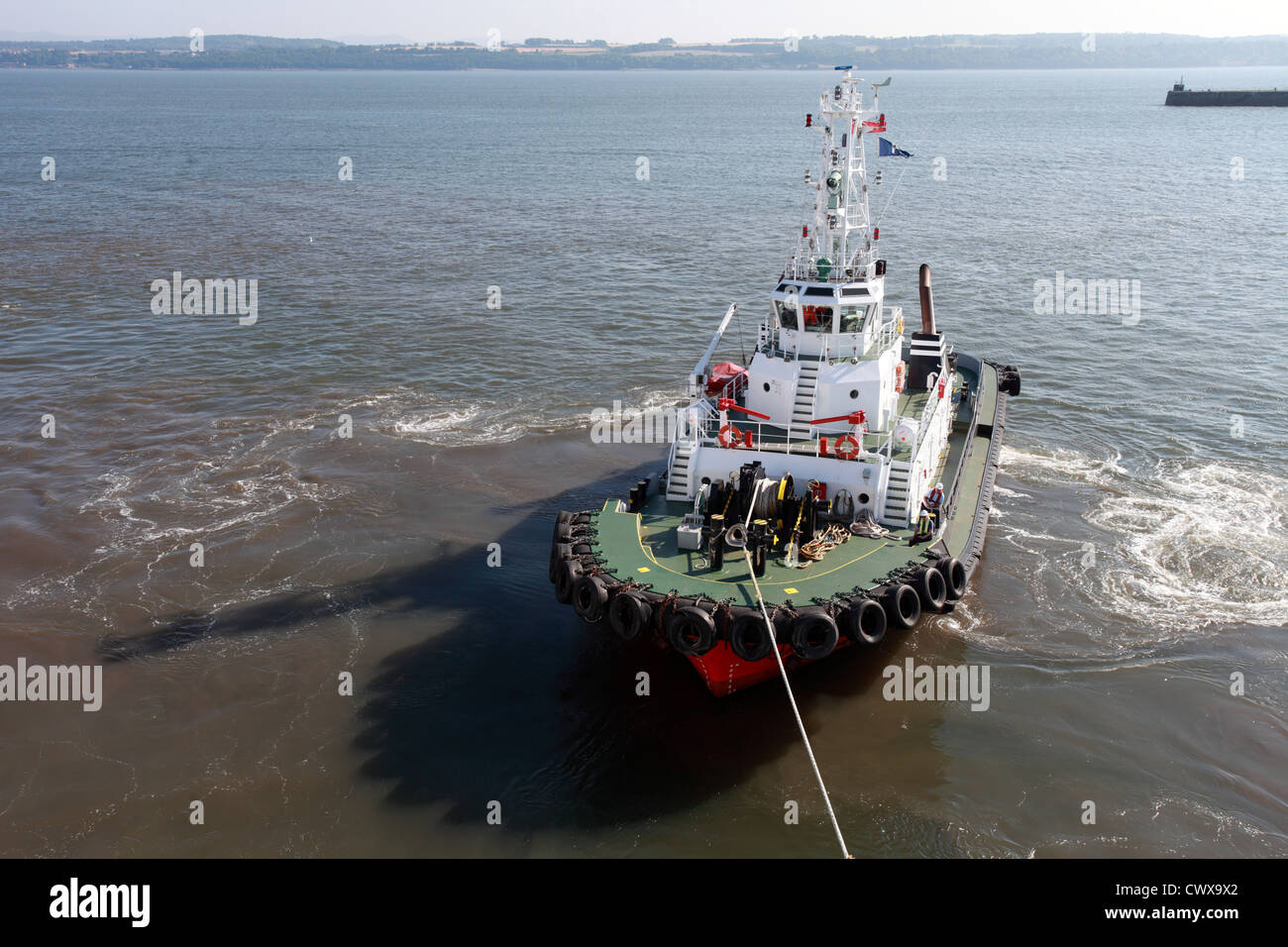 Tugboat in action pulling a large cruise liner into deeper water in ...