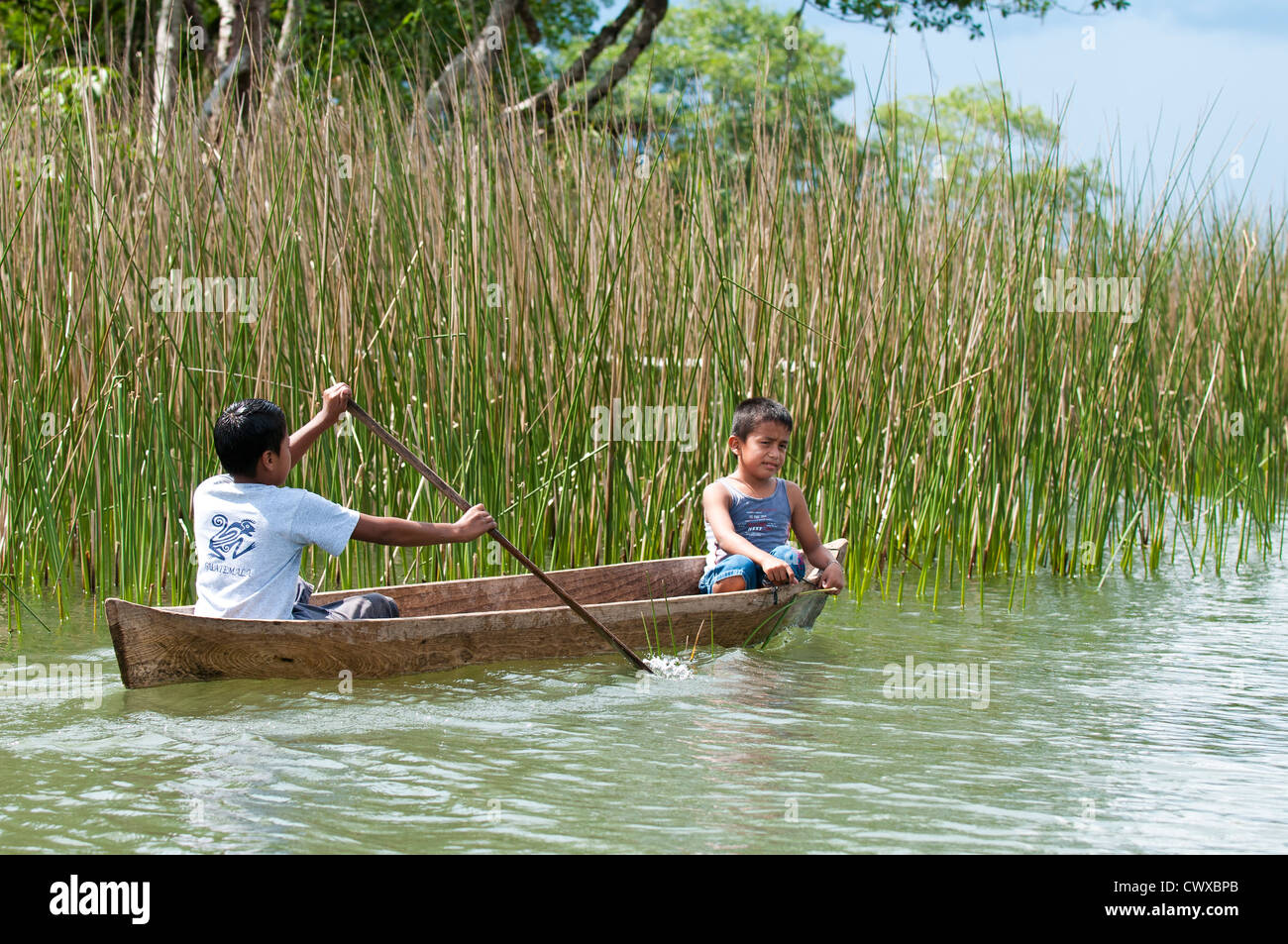 Young indigenous native indian Garifuna boys paddling a dugout canoe on ...