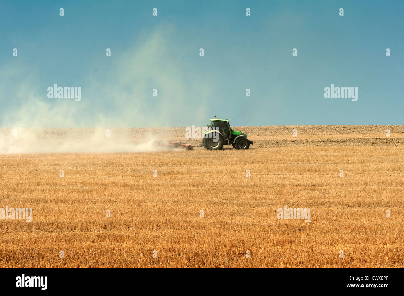 Tractor plowing field on blue sky background Stock Photo - Alamy