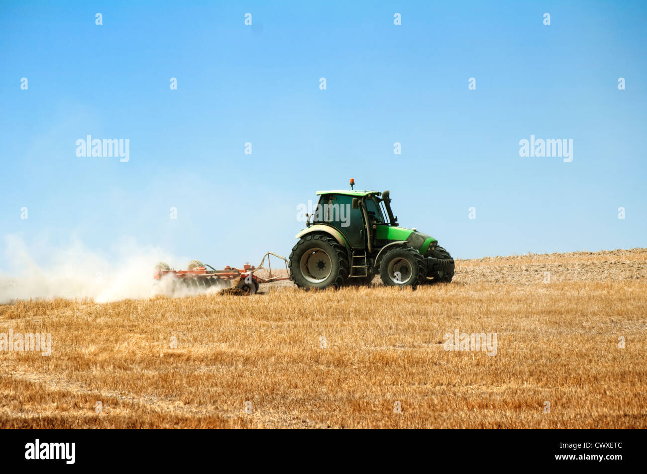 Tractor plowing field on blue sky background Stock Photo - Alamy
