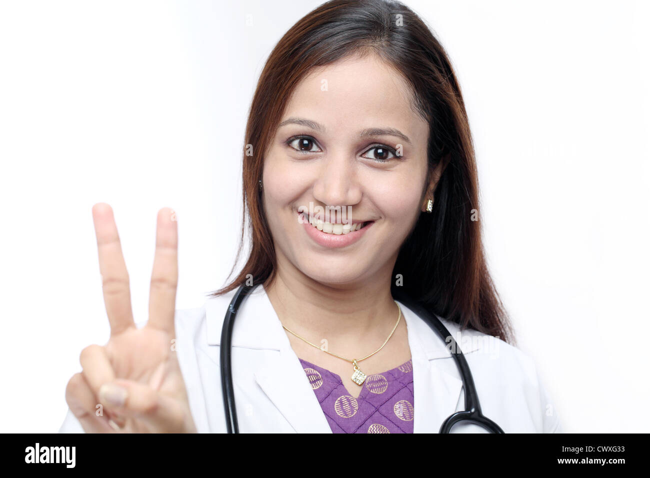 Successful female doctor showing victory sign against white background ...