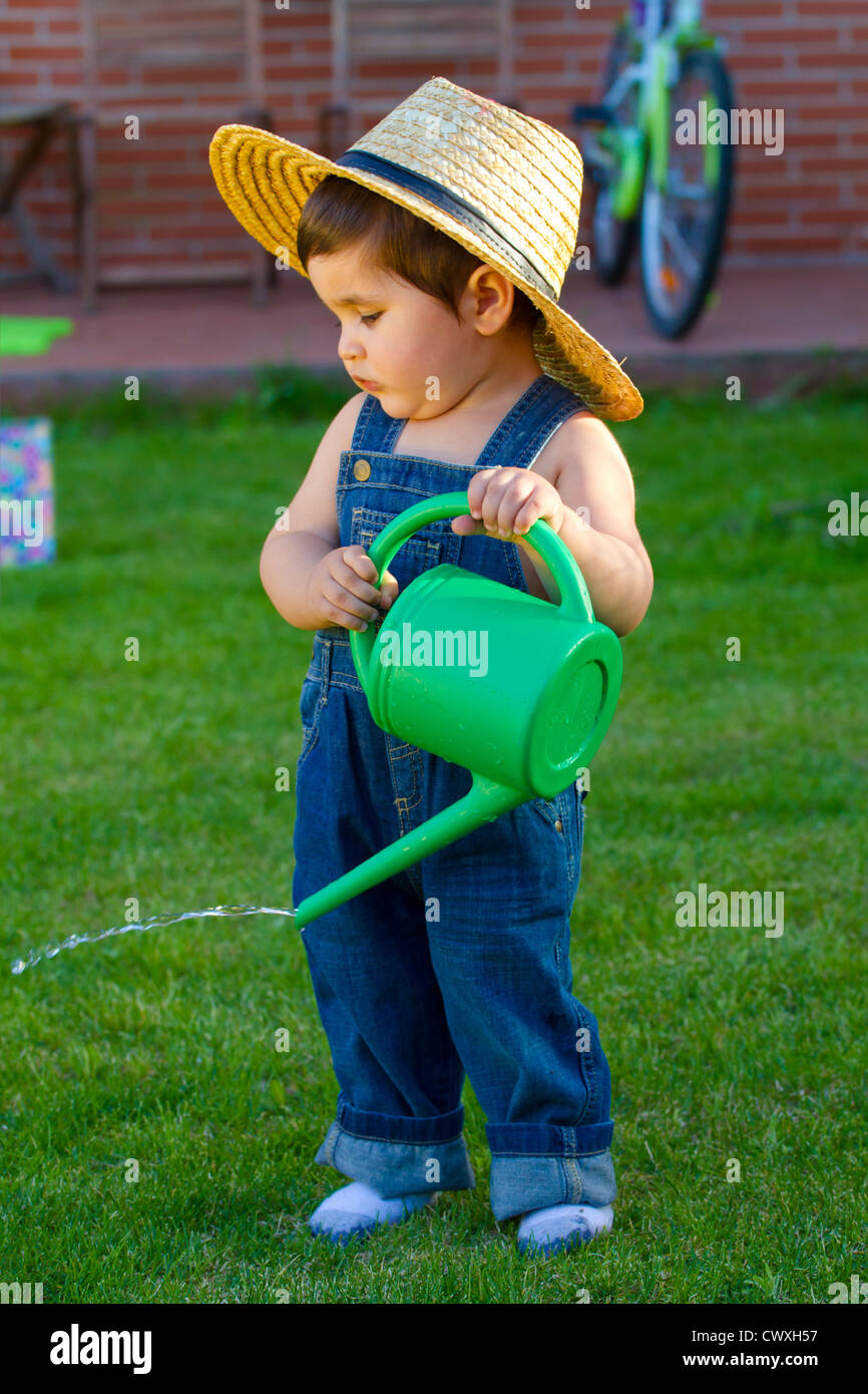little baby boy gardener watering the grass in serious manner Stock ...