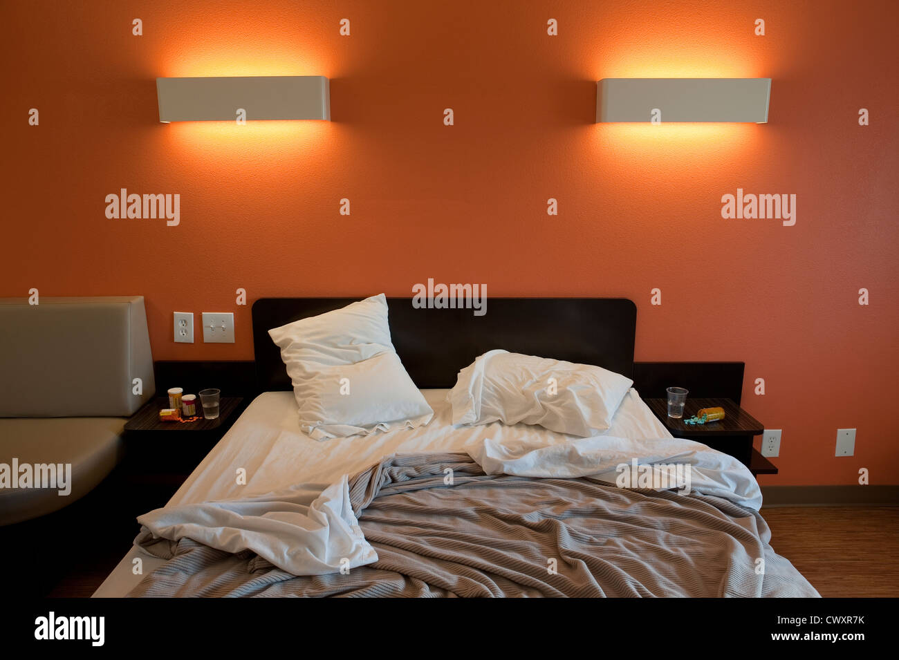 Motel room with bed and medications, pill bottles on side table and ...