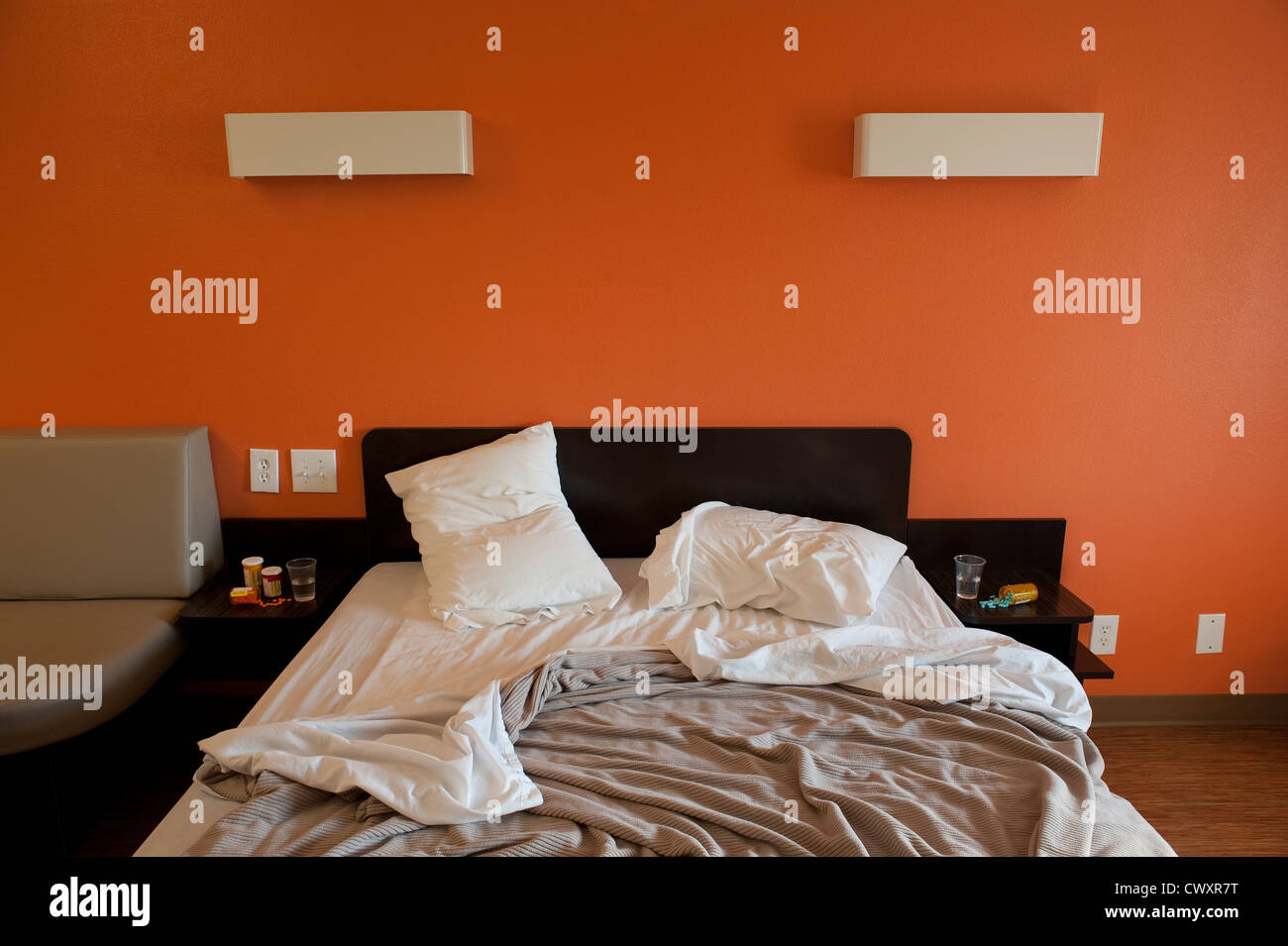 Motel room with bed and medications pill bottles on side table and ...