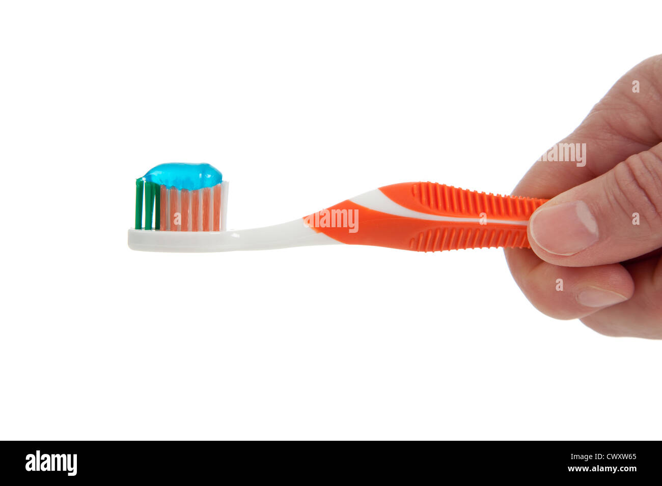 A hand holding an orange toothbrush with toothpaste on a white ...