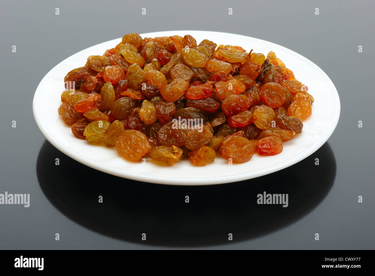 Yellow raisins on a white plate on a white background Stock Photo - Alamy