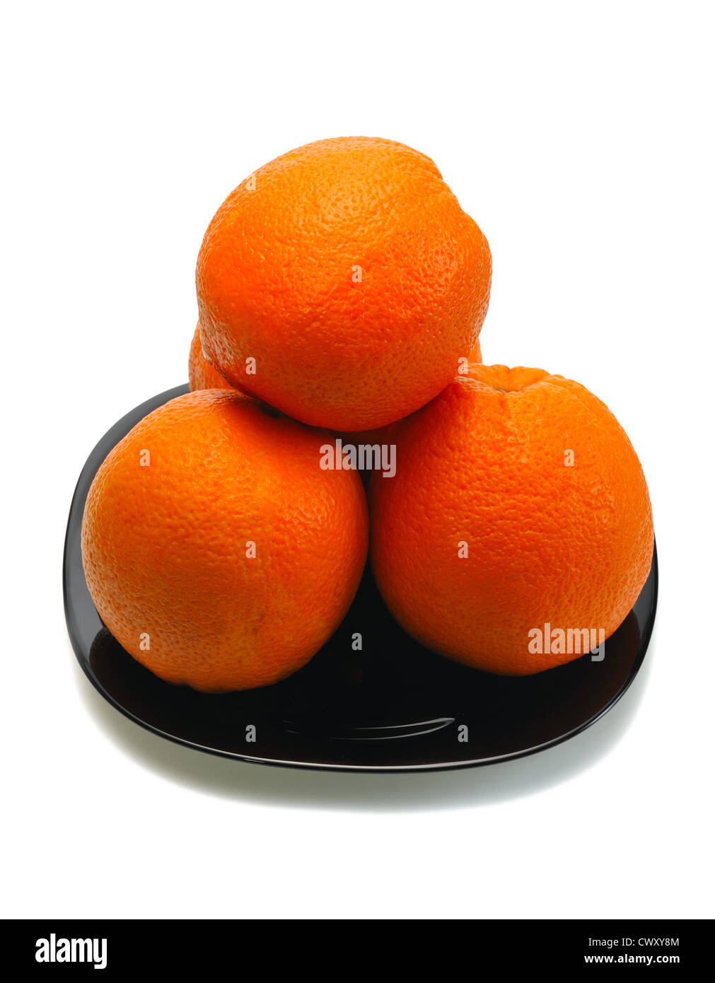 Four oranges and their reflection on a black plate on a white ...