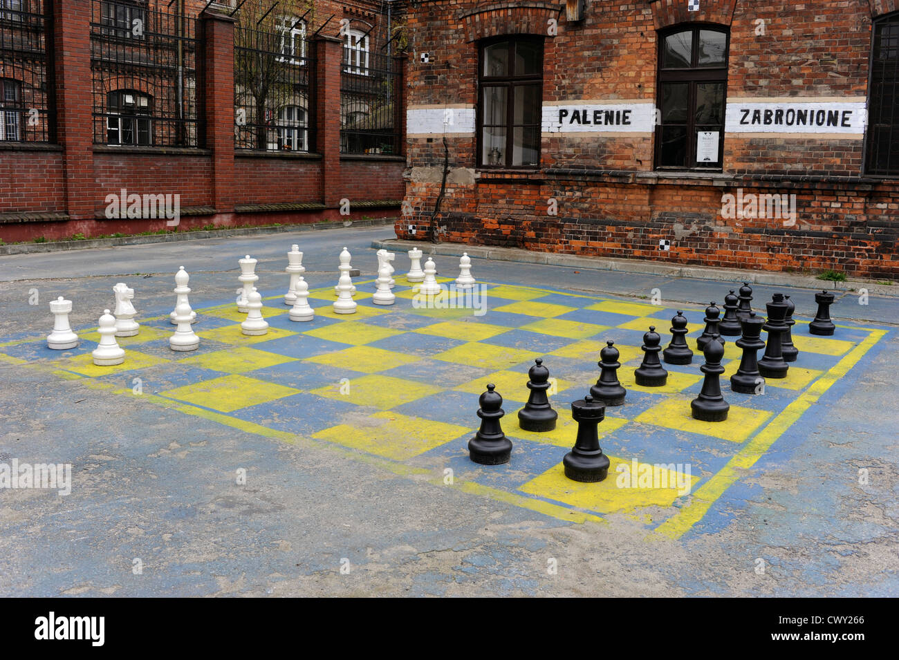 A large checkered board painted on the pavement with huge chess pieces ...