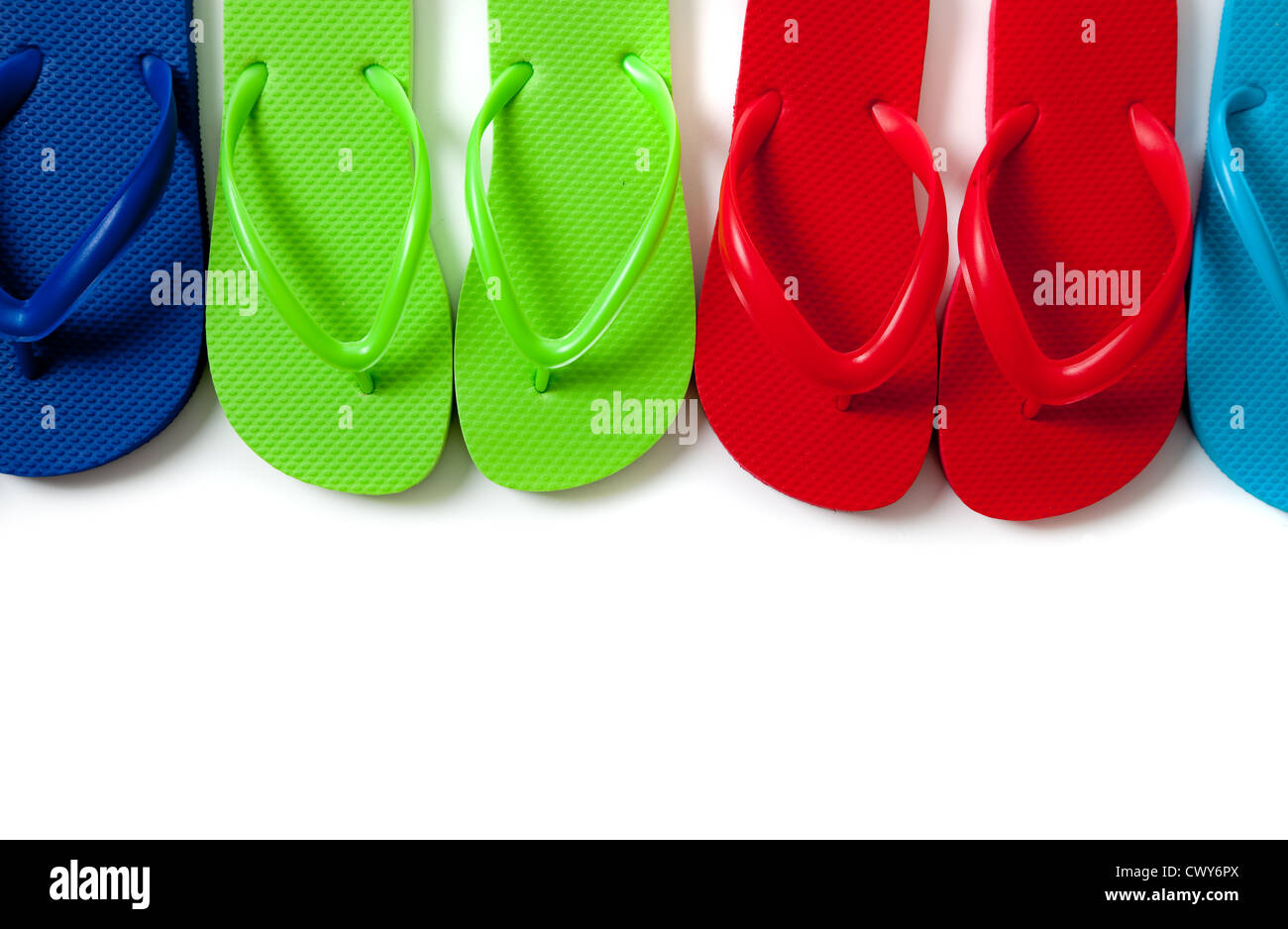 A row of multi-colored flipflops on a white background with copy space ...