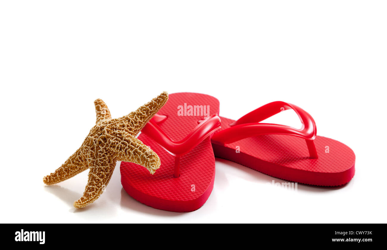 Red flipflops and a starfish on a white background with copy space ...
