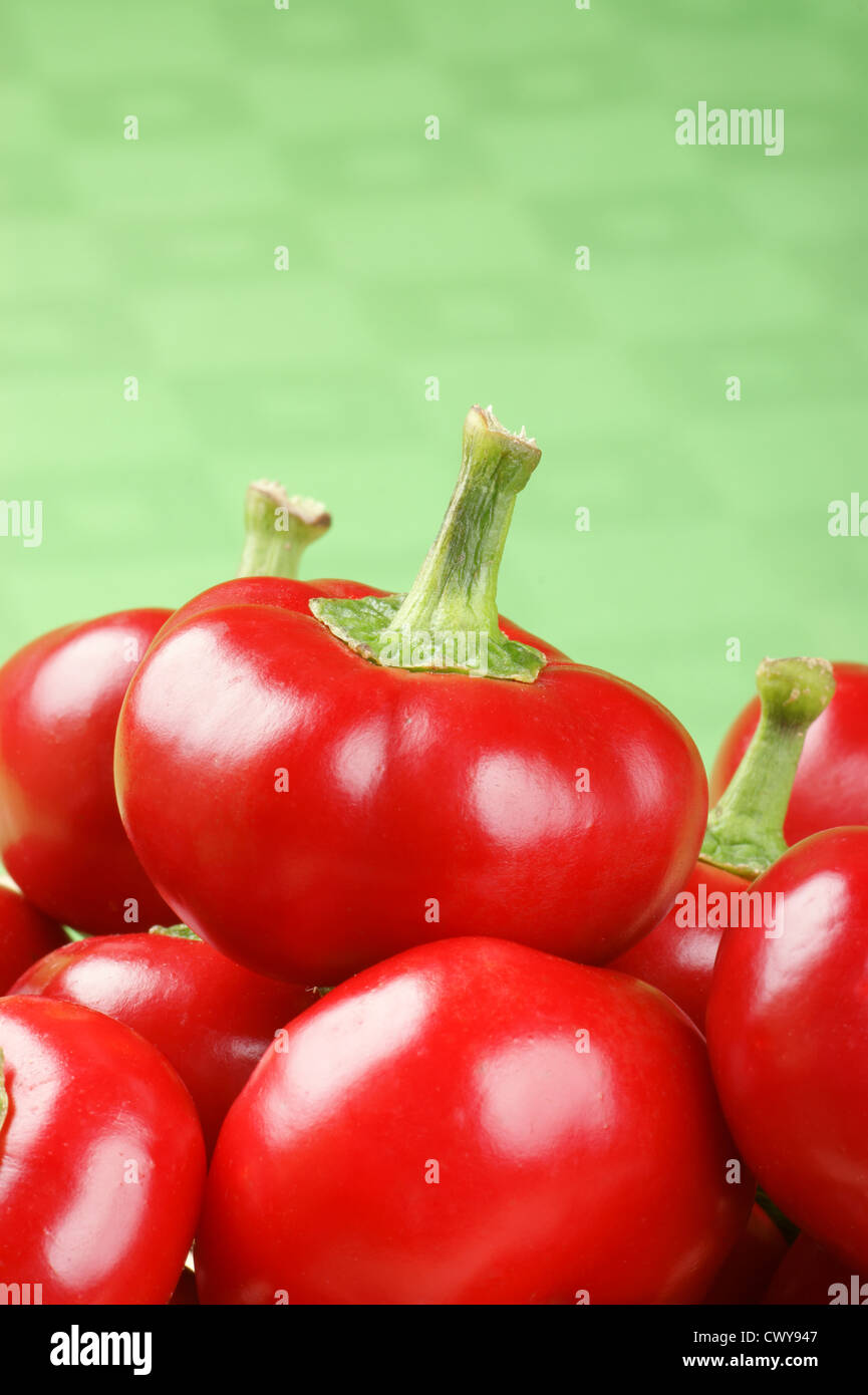 Round, red chili peppers over a green background Stock Photo - Alamy