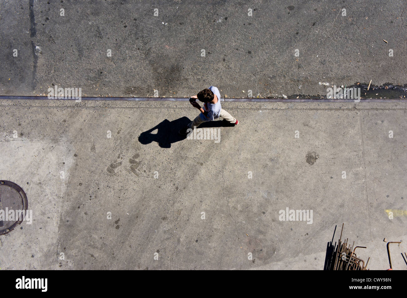 Aerial view of a young man walking whilst looking at his phone on a New ...