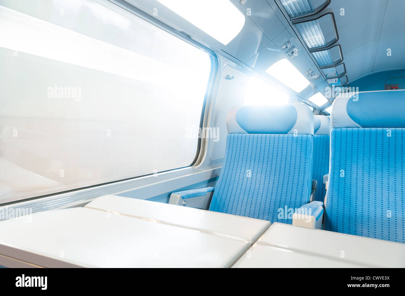 Inside cabin of modern express train. Nobody in blue chairs at window ...
