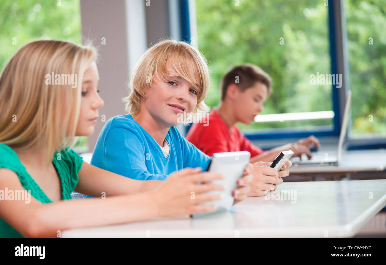 Schoolchildren using laptop and tablet pc in classroom Stock Photo - Alamy