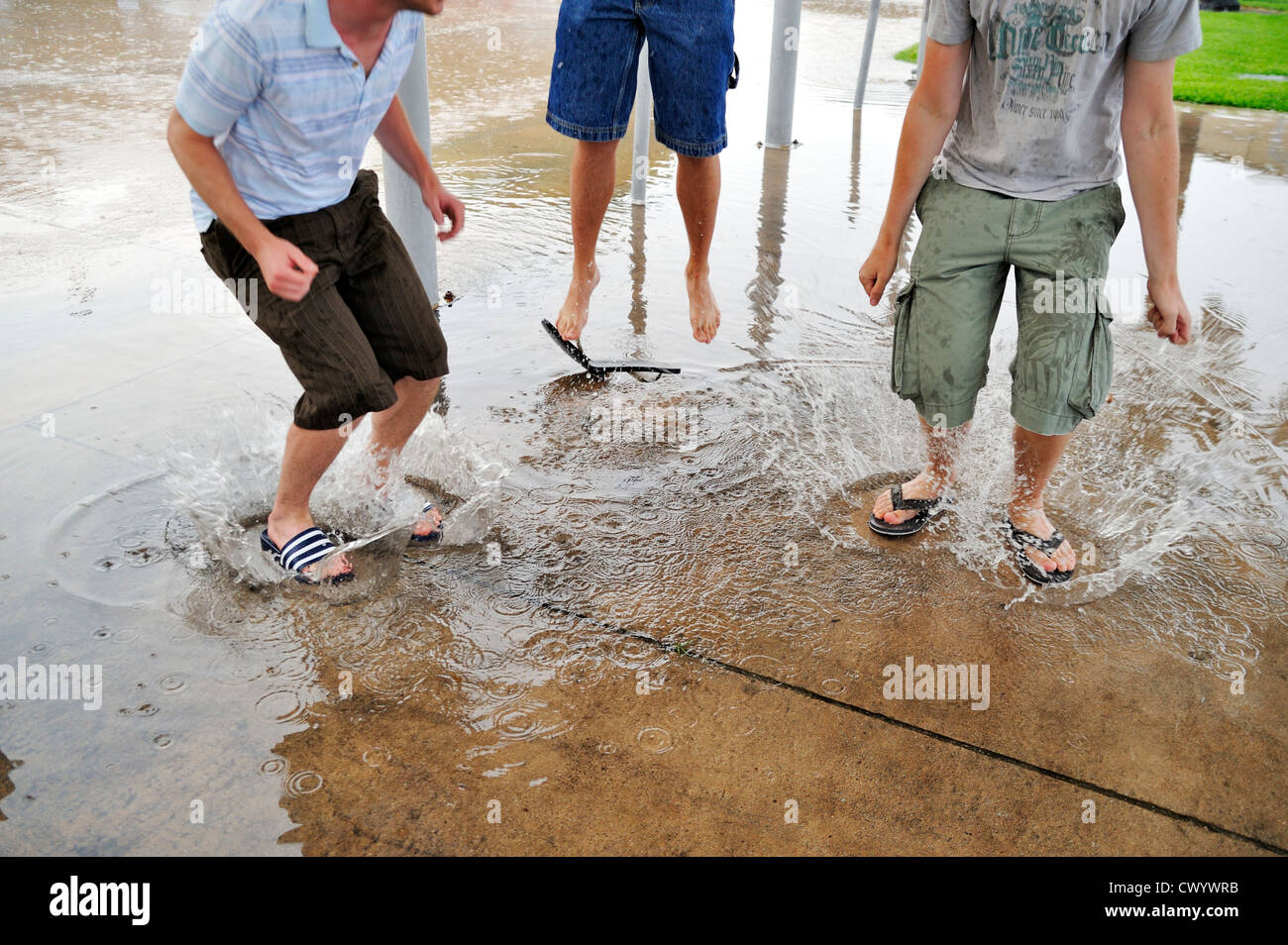 Three young men jumping in puddles Stock Photo - Alamy