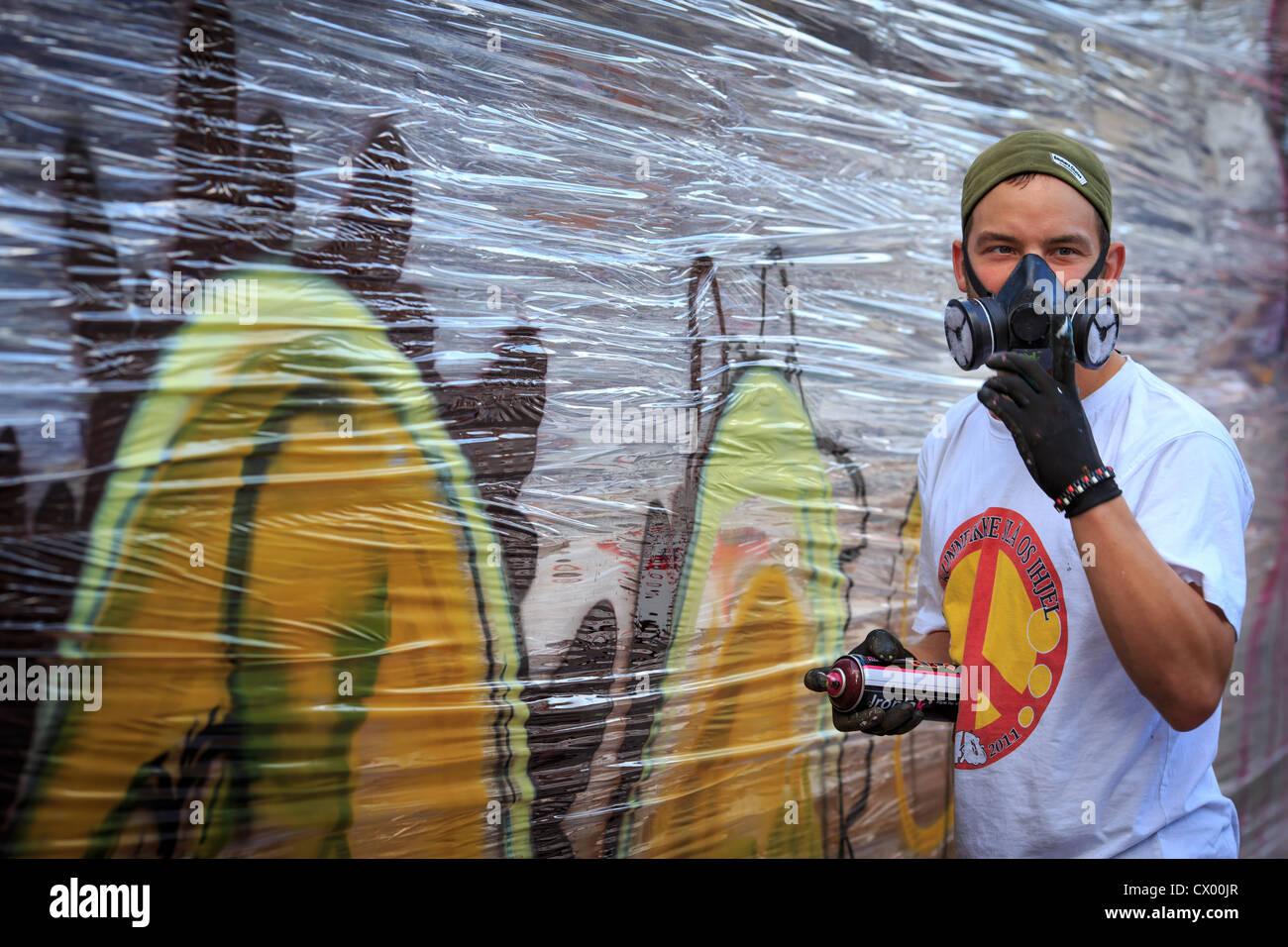 A graffiti painter with a mask paints a bus during a street festival in ...