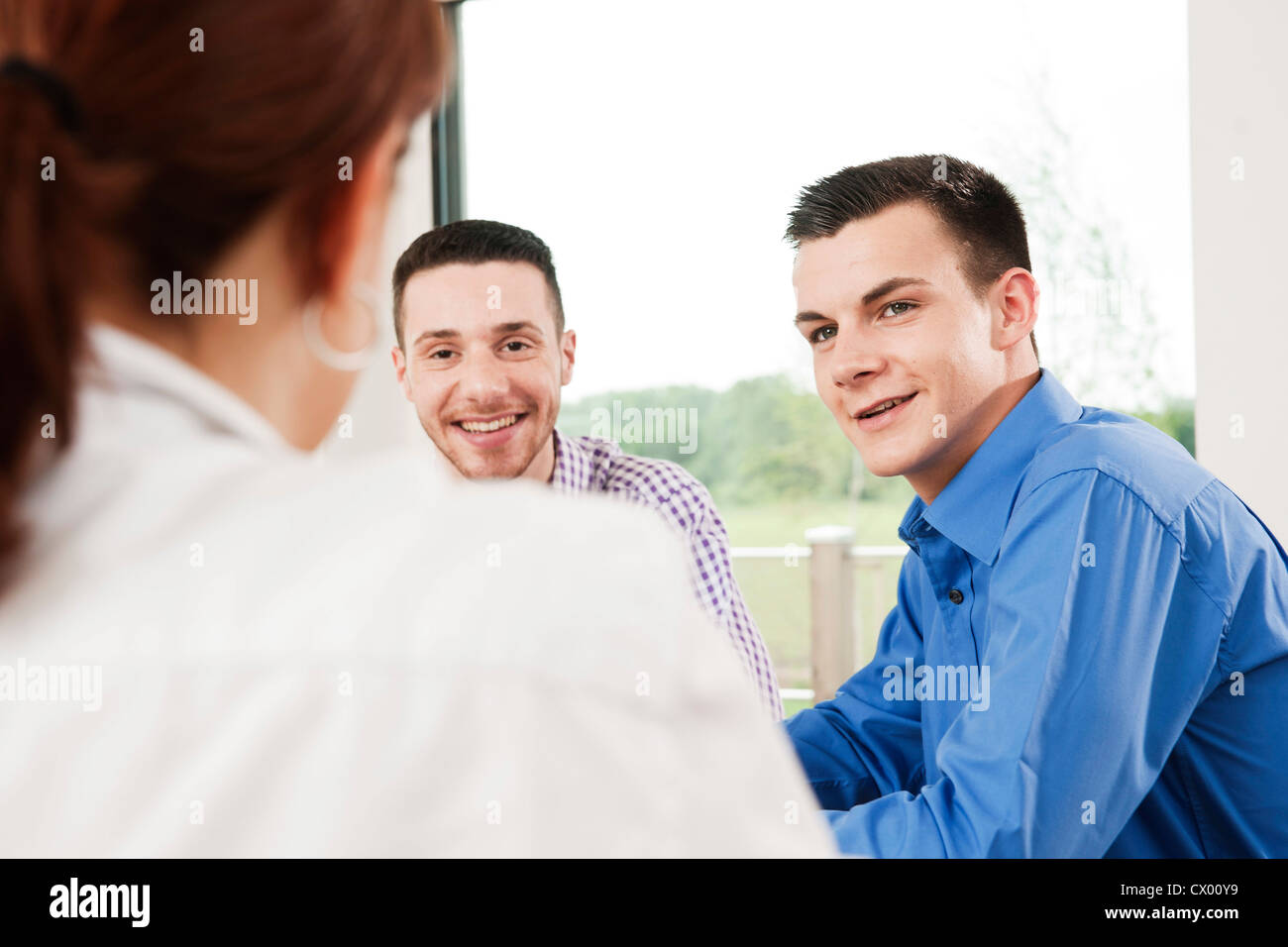 Two young men and a woman having a meeting Stock Photo - Alamy