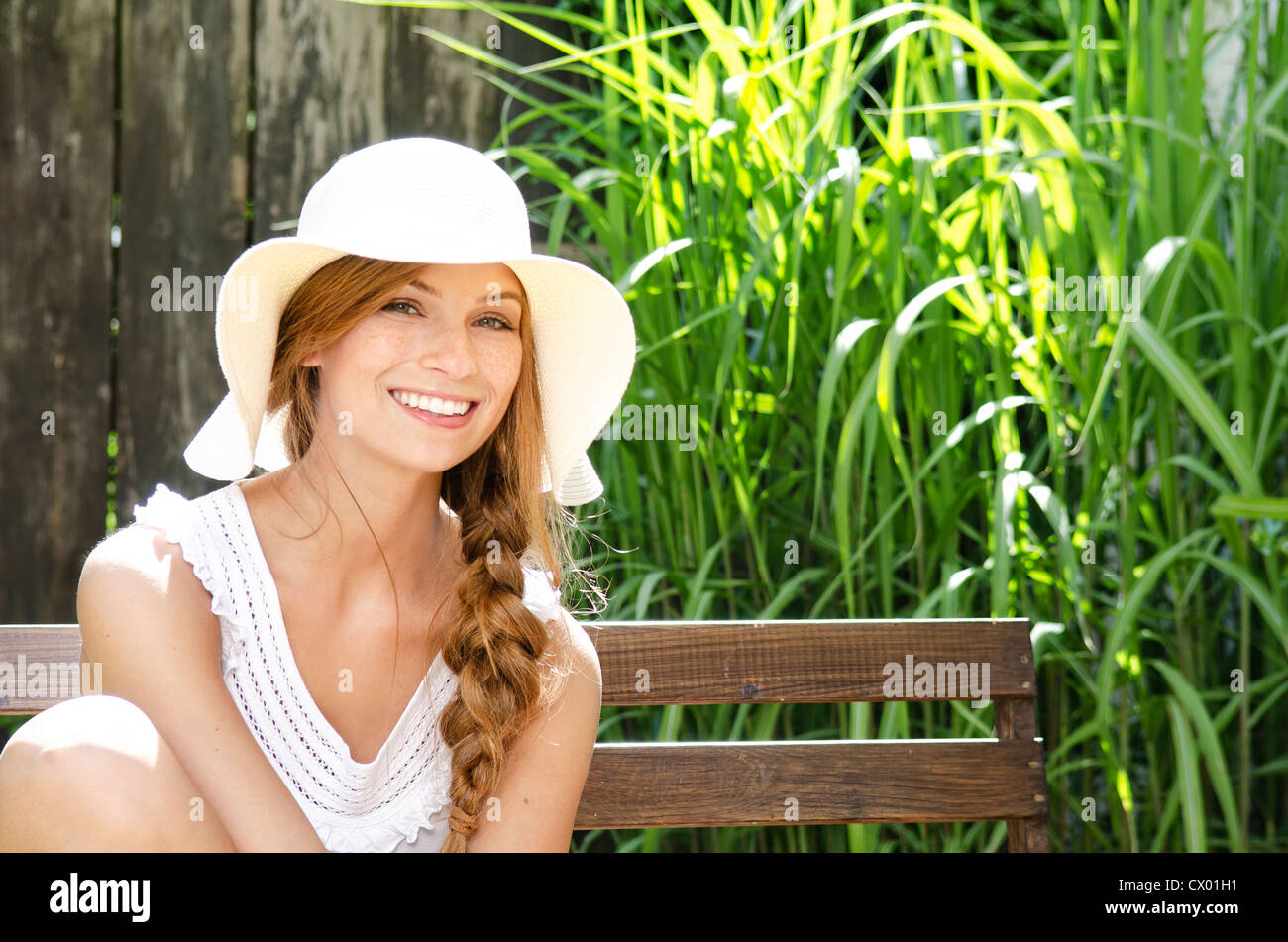 Smiling young woman sitting on bench, portrait Stock Photo - Alamy