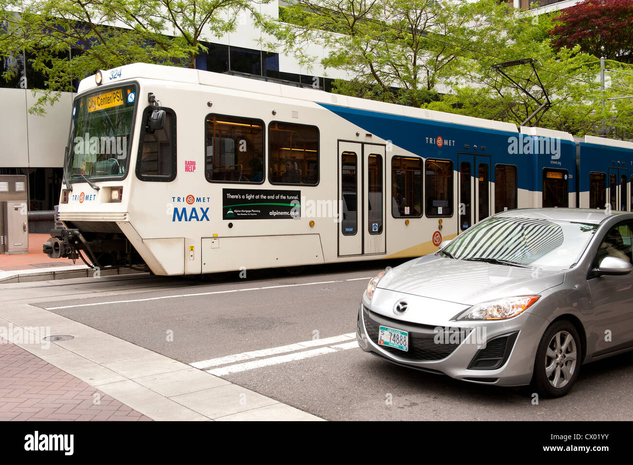 A light rail train and an automobile at an intersection in downtown ...