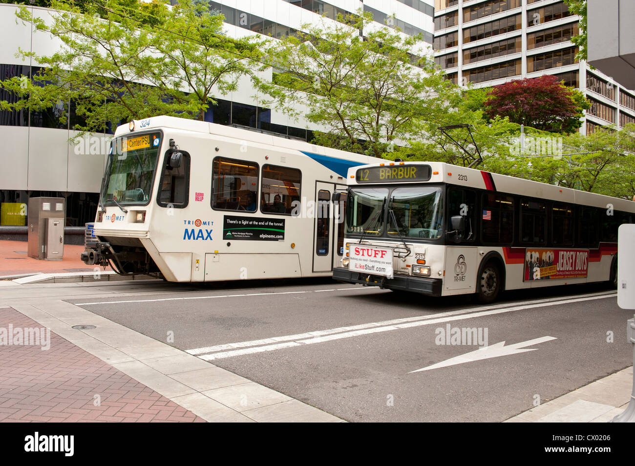 A light rail train and a city bus at an intersection in downtown ...