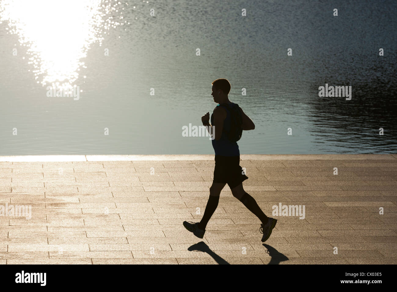 Man running in early morning light reflection Stock Photo - Alamy