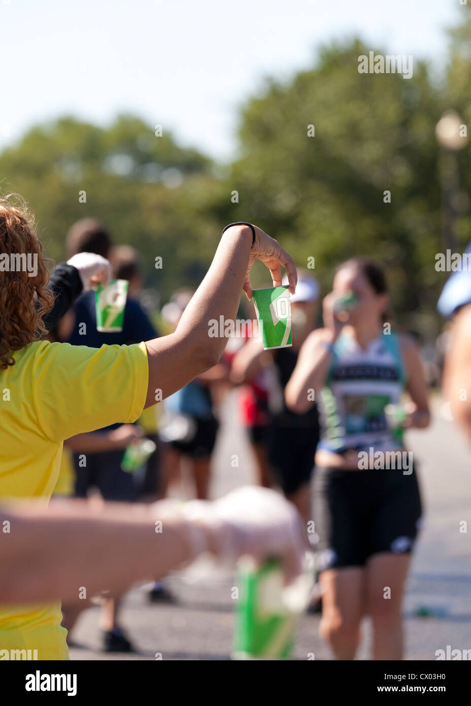 Marathon volunteer offering water to runners Stock Photo - Alamy