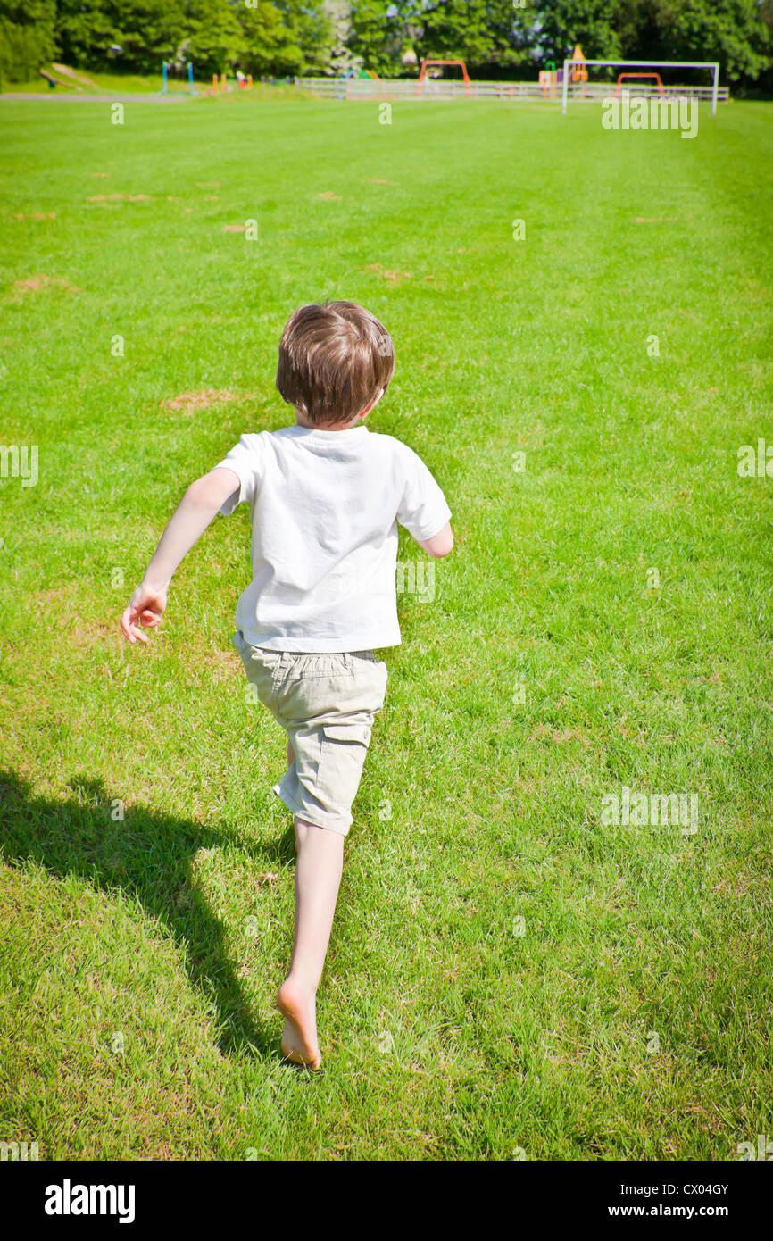A young boy running across a playing filed Stock Photo - Alamy
