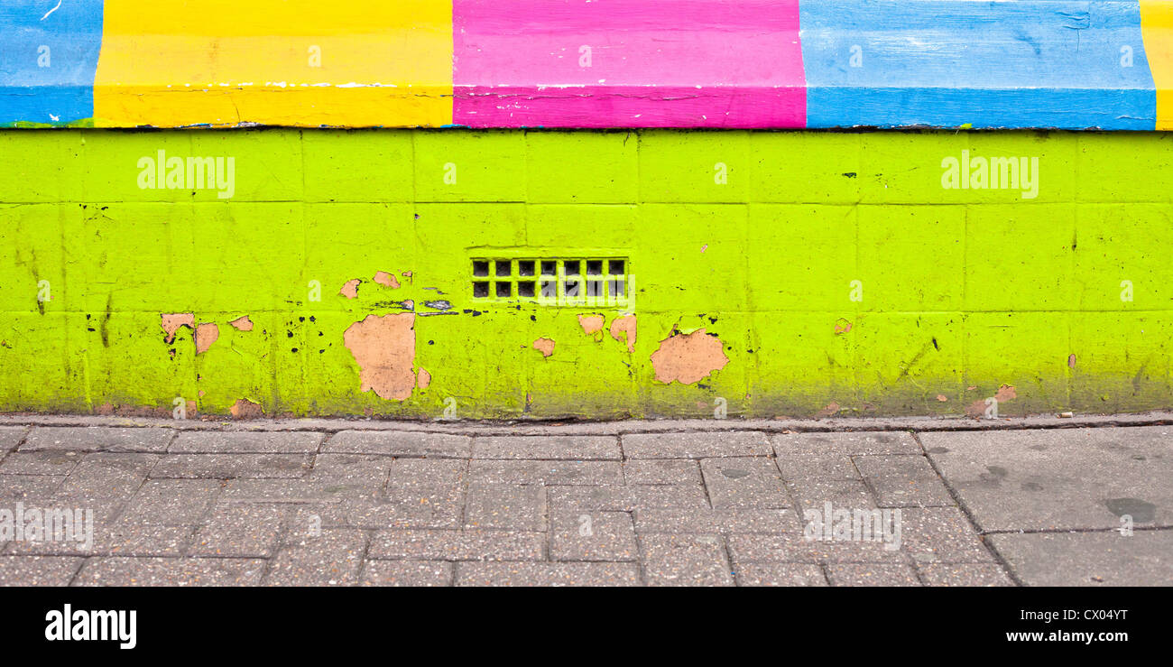 A vibrant wall next to a pavement showing damage Stock Photo - Alamy