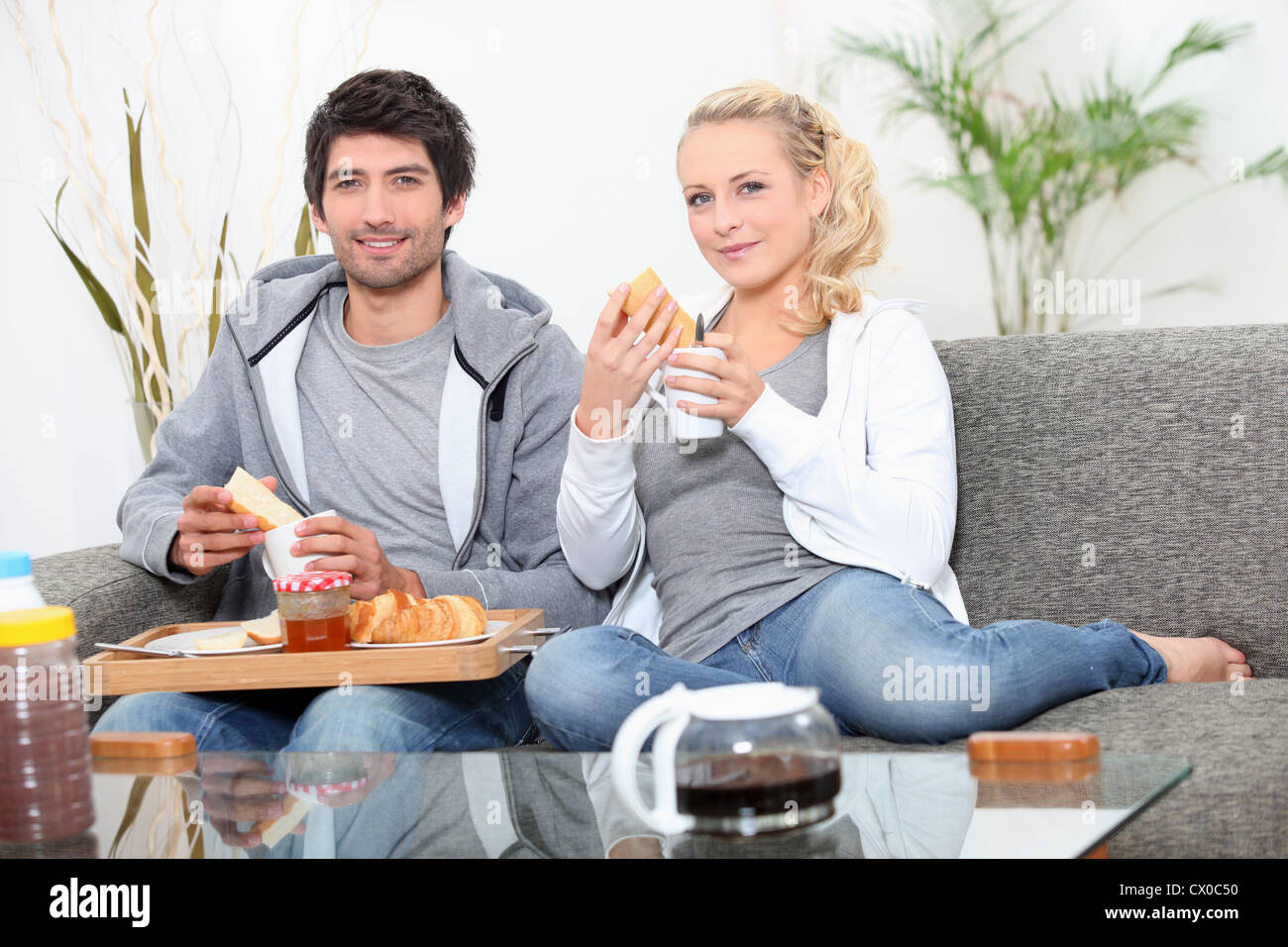 Couple having breakfast on couch Stock Photo - Alamy