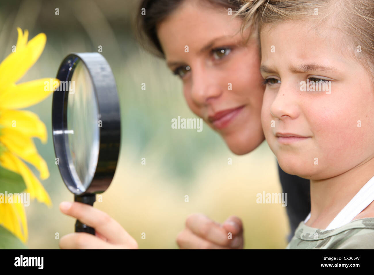 Girl with magnifying glass watching flower Stock Photo - Alamy