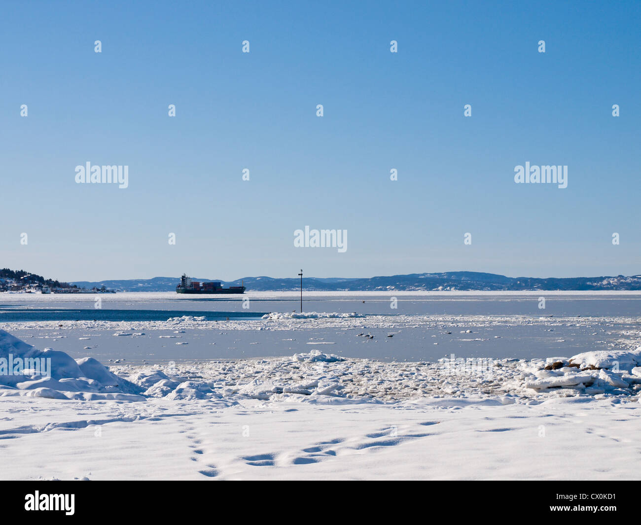 Container ship working its way through the fjord ice in Oslofjorden ...