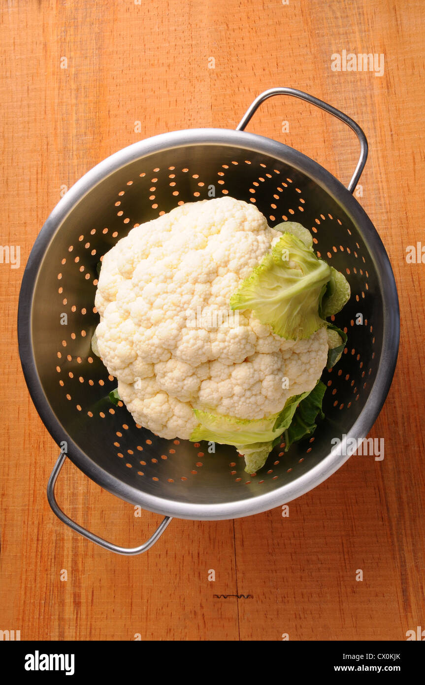 Fresh picked cauliflower in a metal colander on rustic wooden table ...