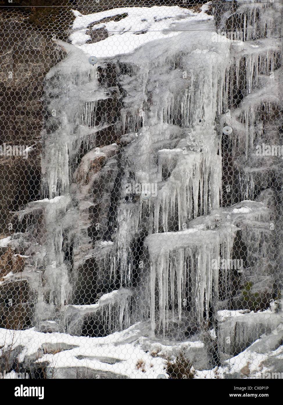 Icicles from trickling water over rocks covered by wire mesh so as not ...