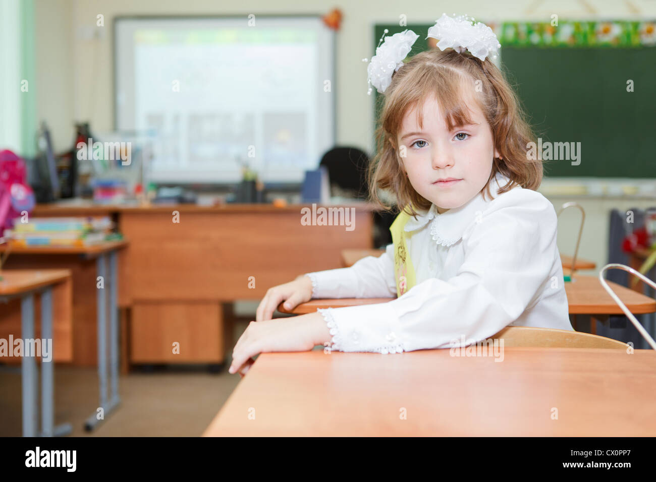 Small girl sitting in class room desk in uniform, Russian elementary ...