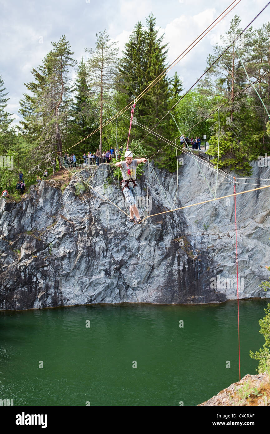 Man transition the rope bridge over a flooded marble quarry in Ruskeala ...