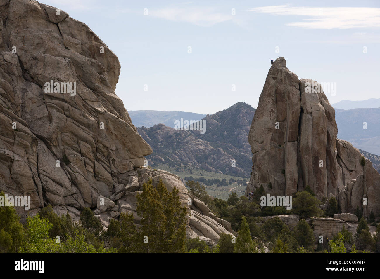 A rock climber is silhouetted at the top of a pinnacle, City of Rocks ...