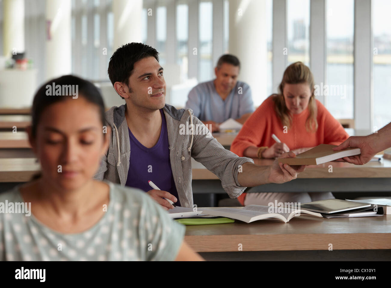 Mature students in class, man receiving book Stock Photo - Alamy