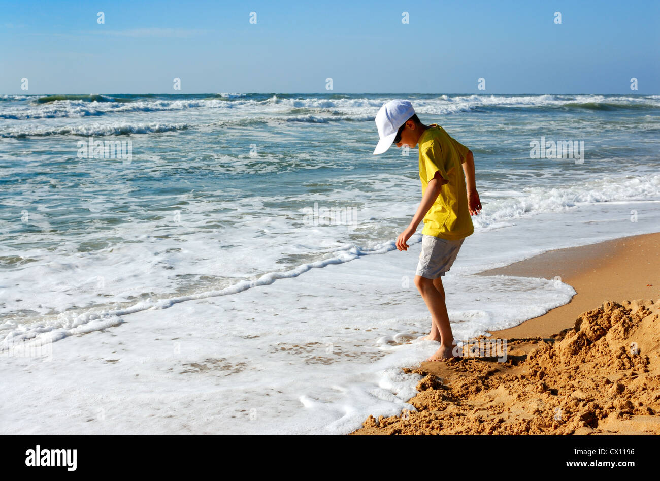 Boy playing with sand on the seashore Stock Photo - Alamy