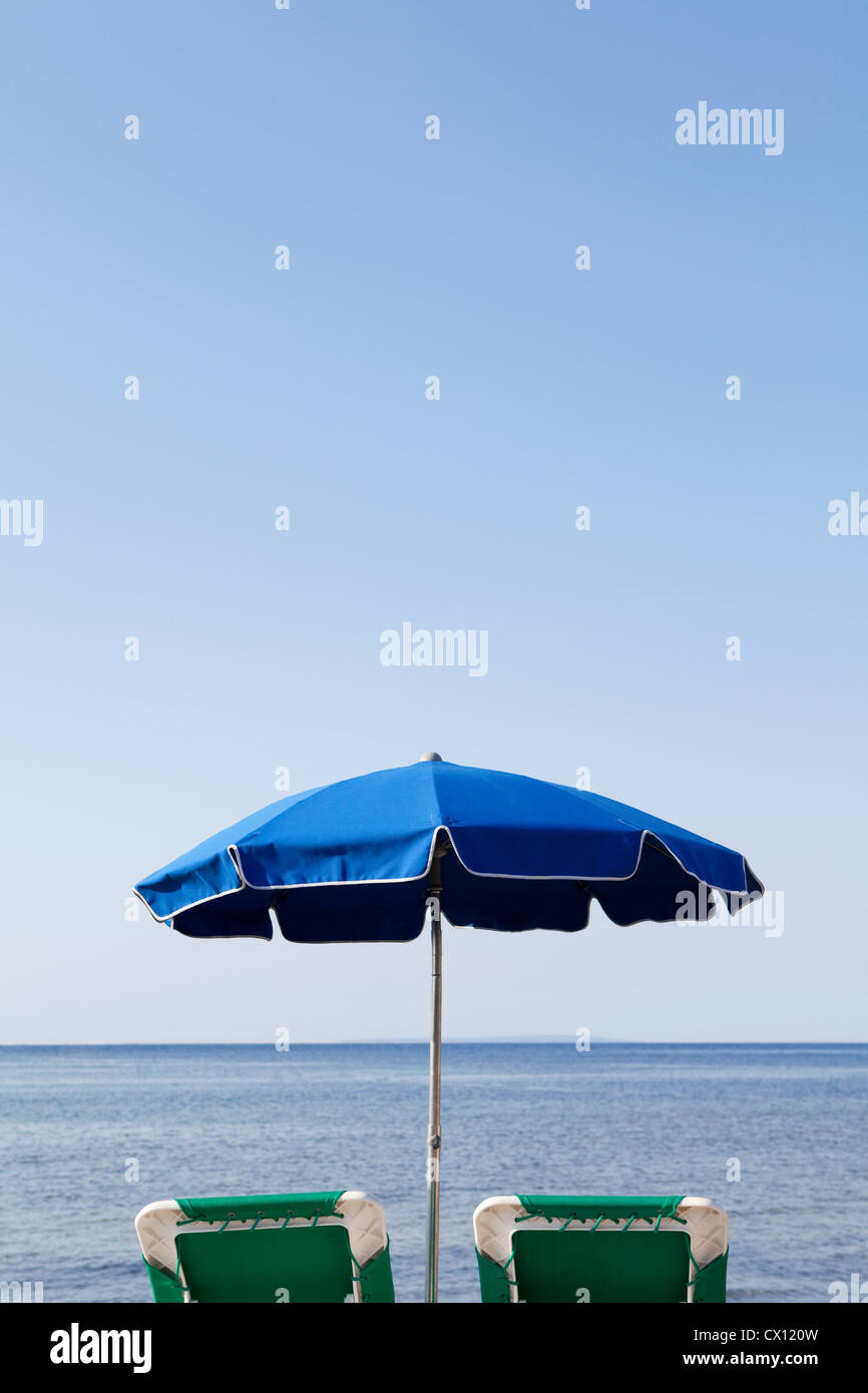 Blue parasol and sun loungers by the sea Stock Photo - Alamy