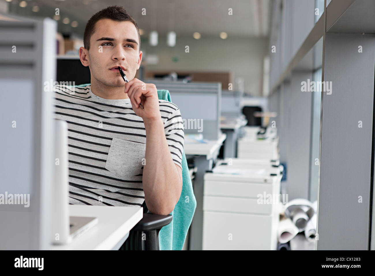 Man chewing pen at desk Stock Photo - Alamy