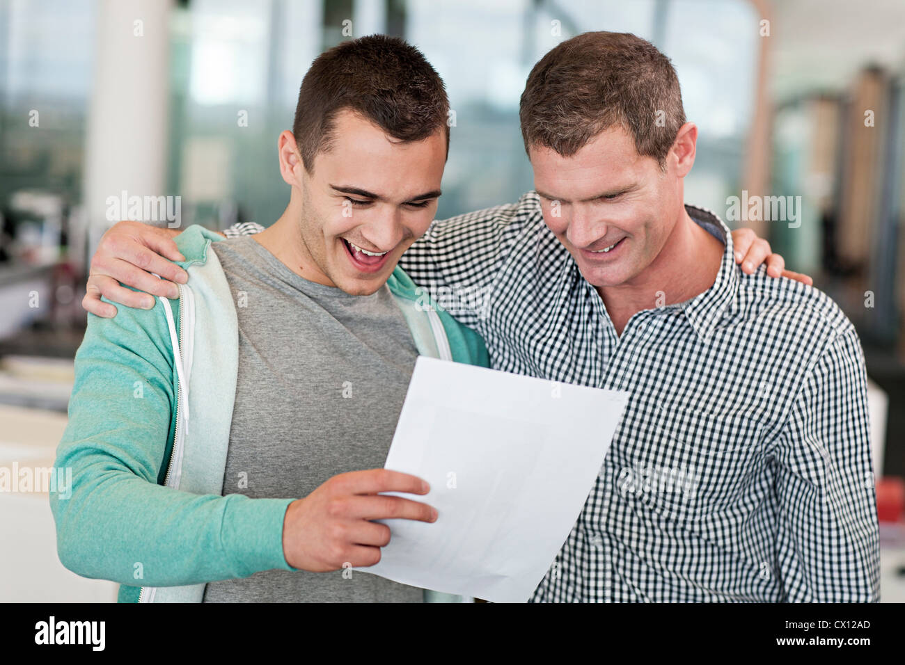 Two men reading document, arms around each other Stock Photo - Alamy